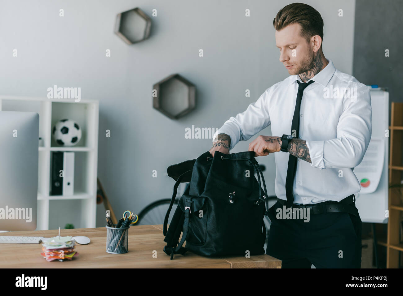 handsome young tattooed businessman opening backpack at workplace Stock ...