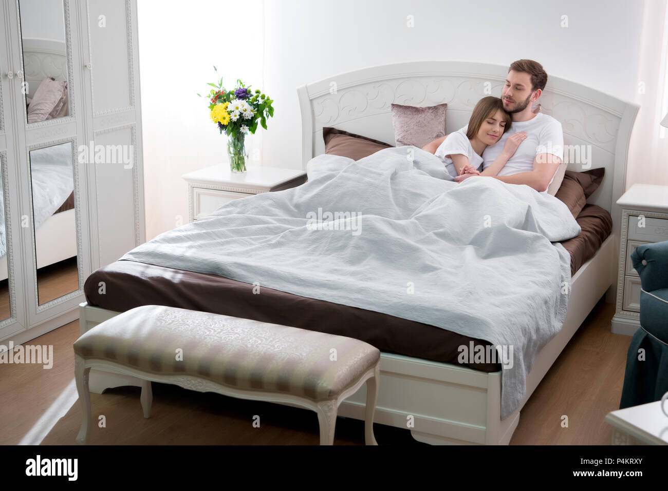 Young female lying on her boyfriend chest in cozy bedroom Stock Photo ...