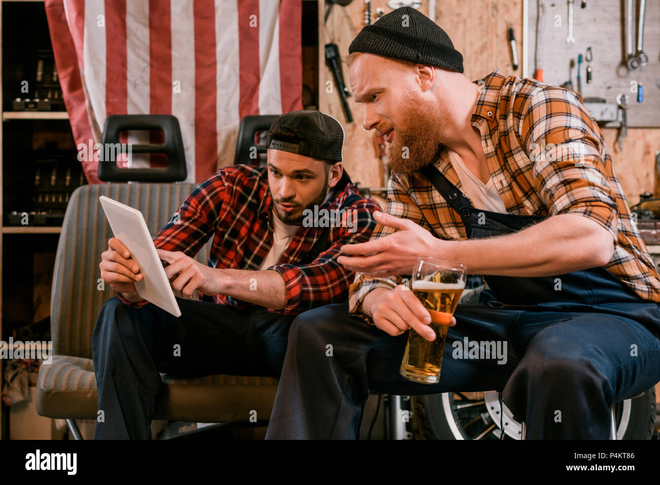 mechanics drinking beer and using tablet together at garage Stock Photo ...