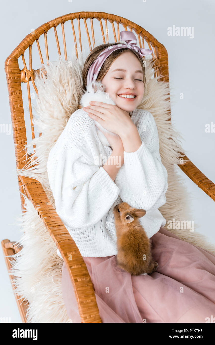 beautiful happy teenage girl hugging rabbits while sitting in rocking ...