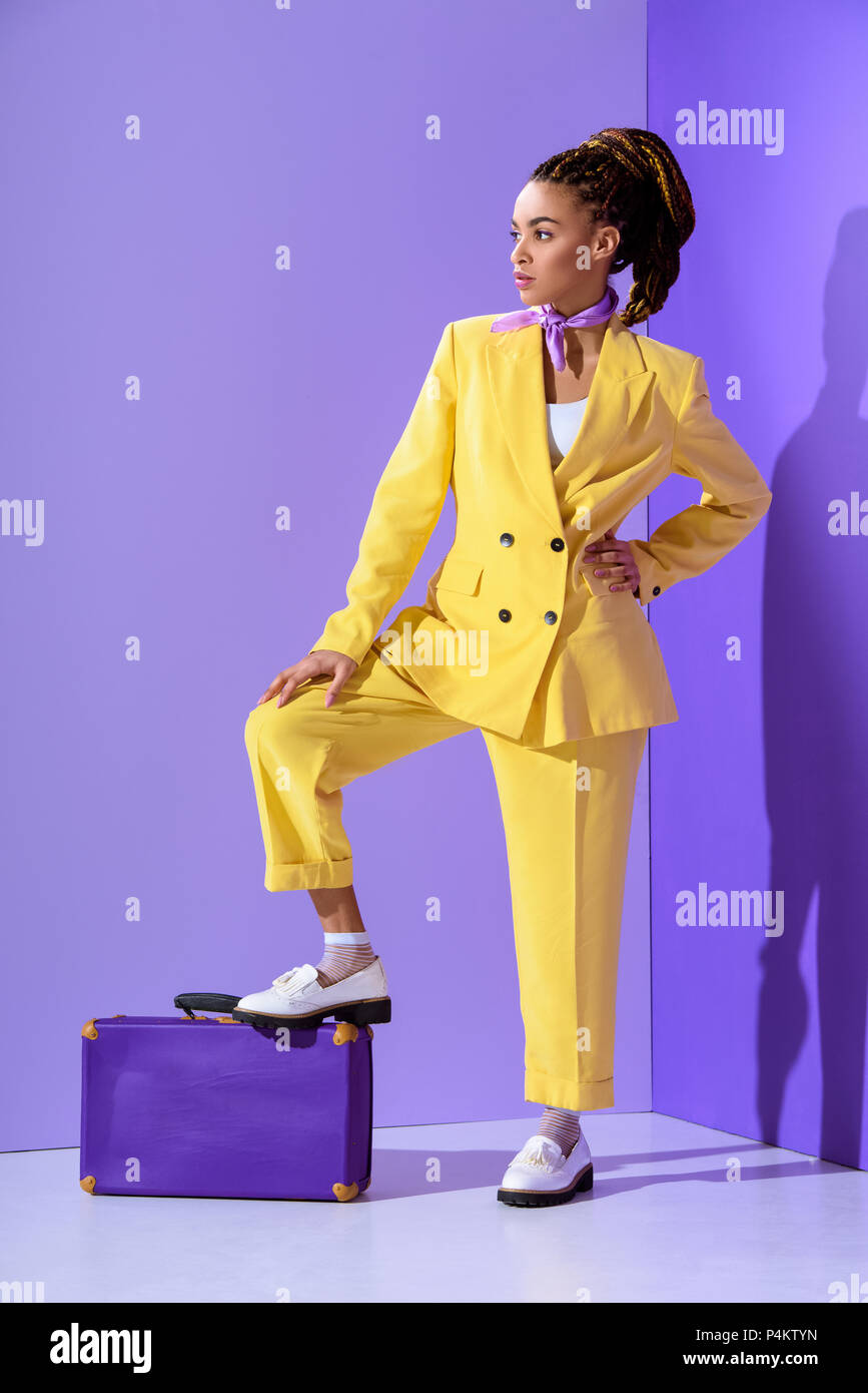 african american model posing in yellow suit with purple suitcase, on ...
