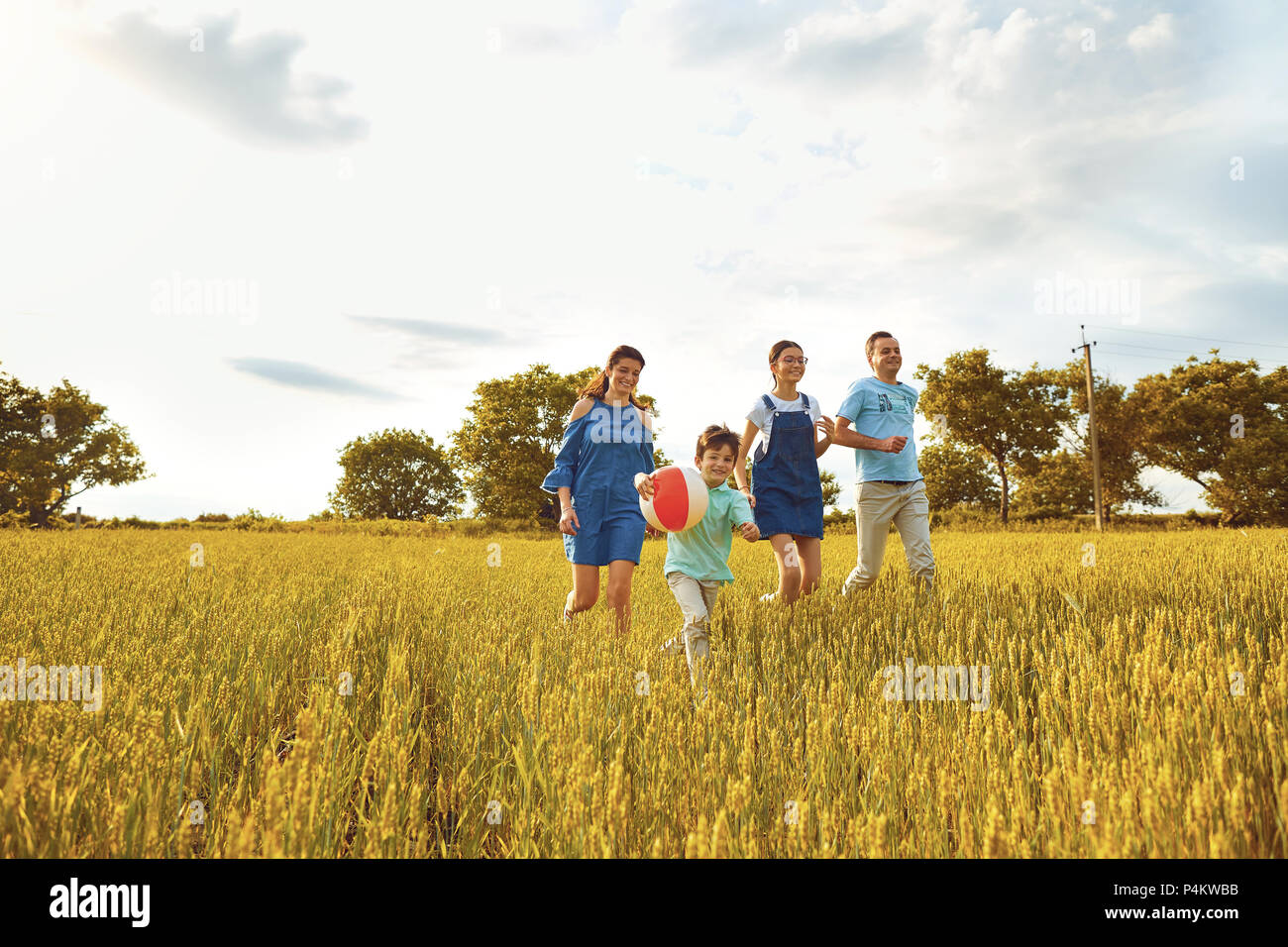 Happy family smiling running on the field in nature Stock Photo - Alamy