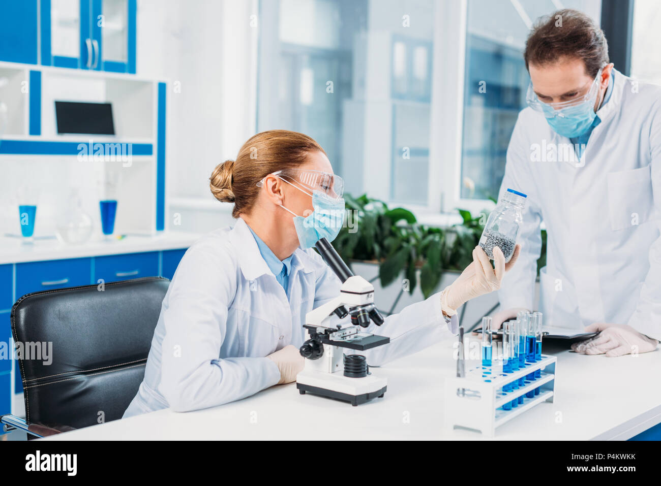 scientists in white coats and goggles working with reagents and ...