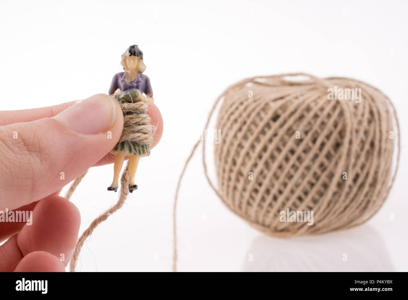 Woman figure in hand beside a linen spool of thread on a white ...