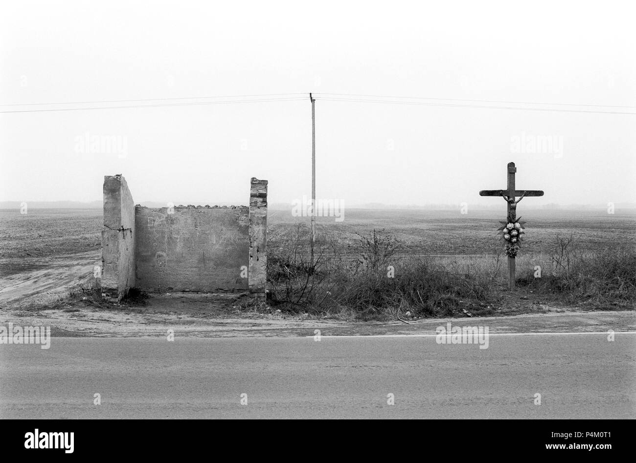 Old bus stop with a crucifix and a electricity pylon behind it. The ...