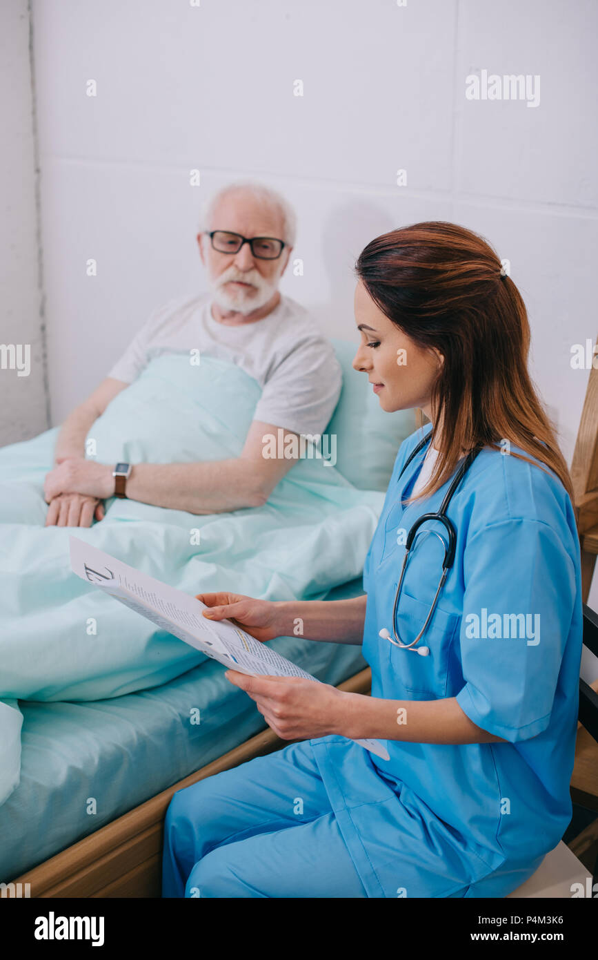 Nurse explaining medical advice to old patient in bed Stock Photo - Alamy