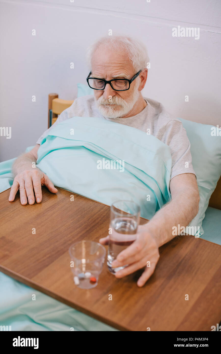 Old man in clinical bed taking medications Stock Photo - Alamy