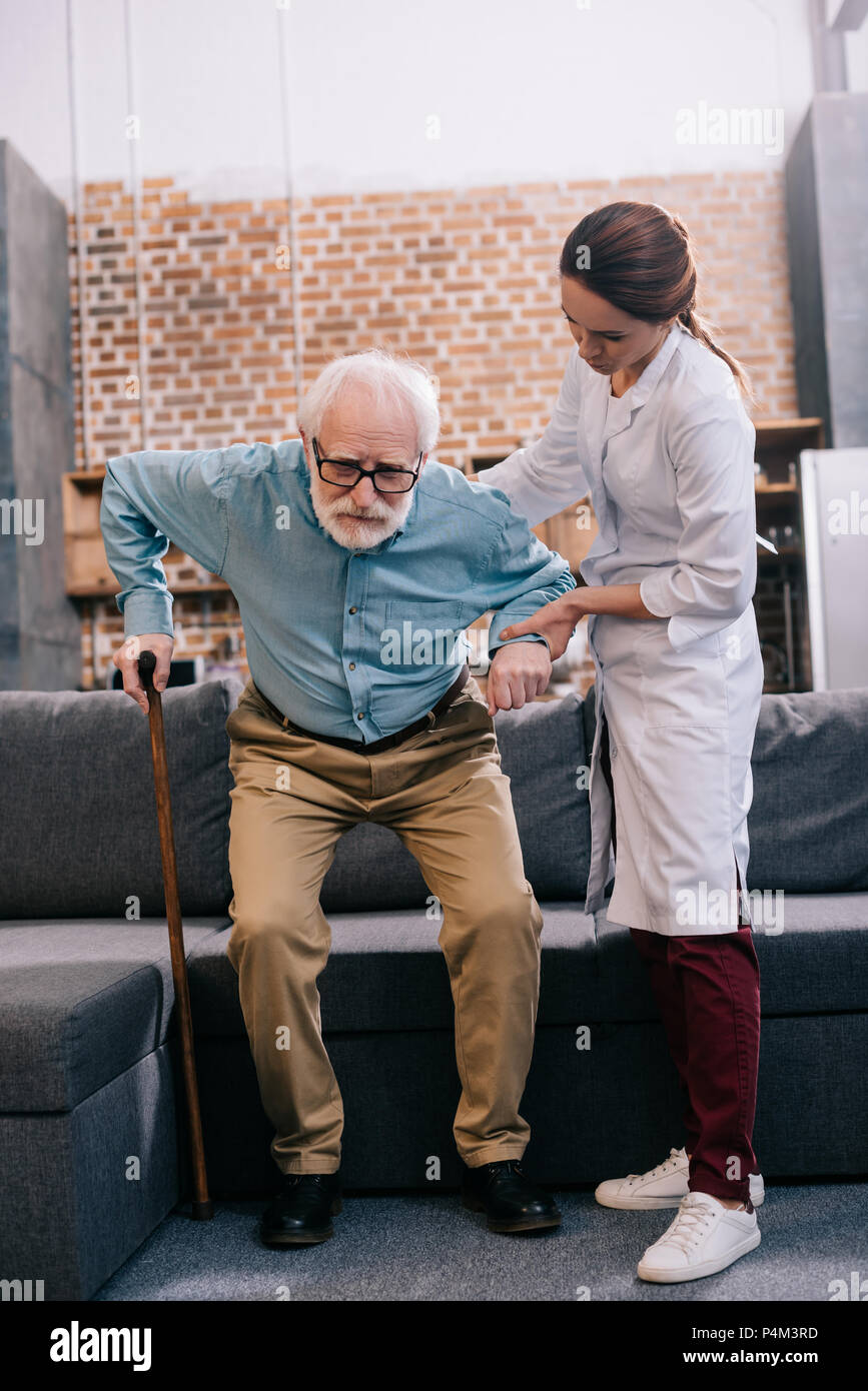 Doctor assisting male patient with cane Stock Photo - Alamy