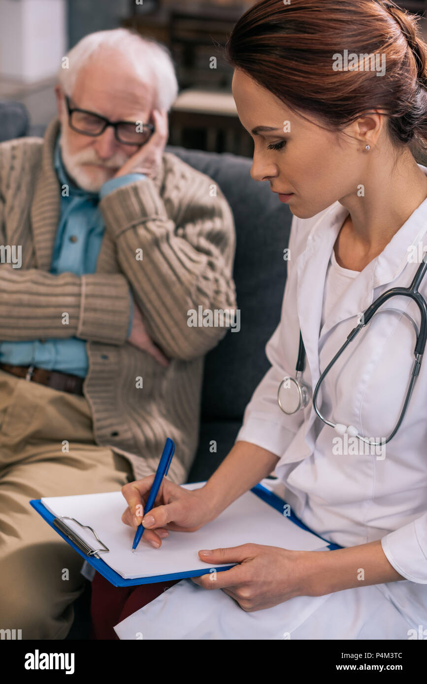 Female doctor writing down senior patient medical complaints Stock ...