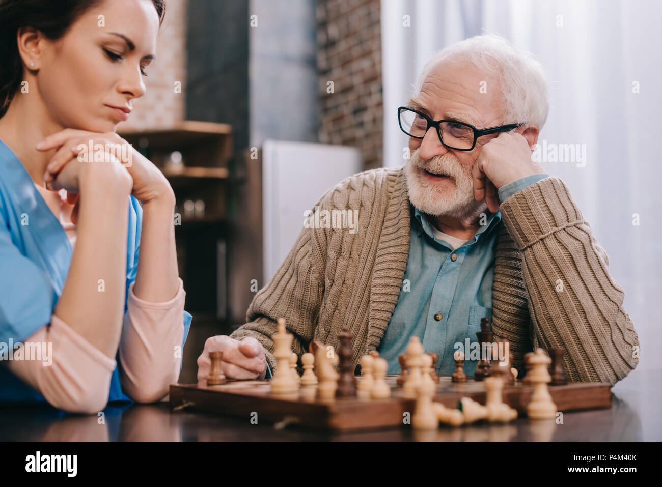 Thoughtful nurse and elder man playing chess Stock Photo - Alamy