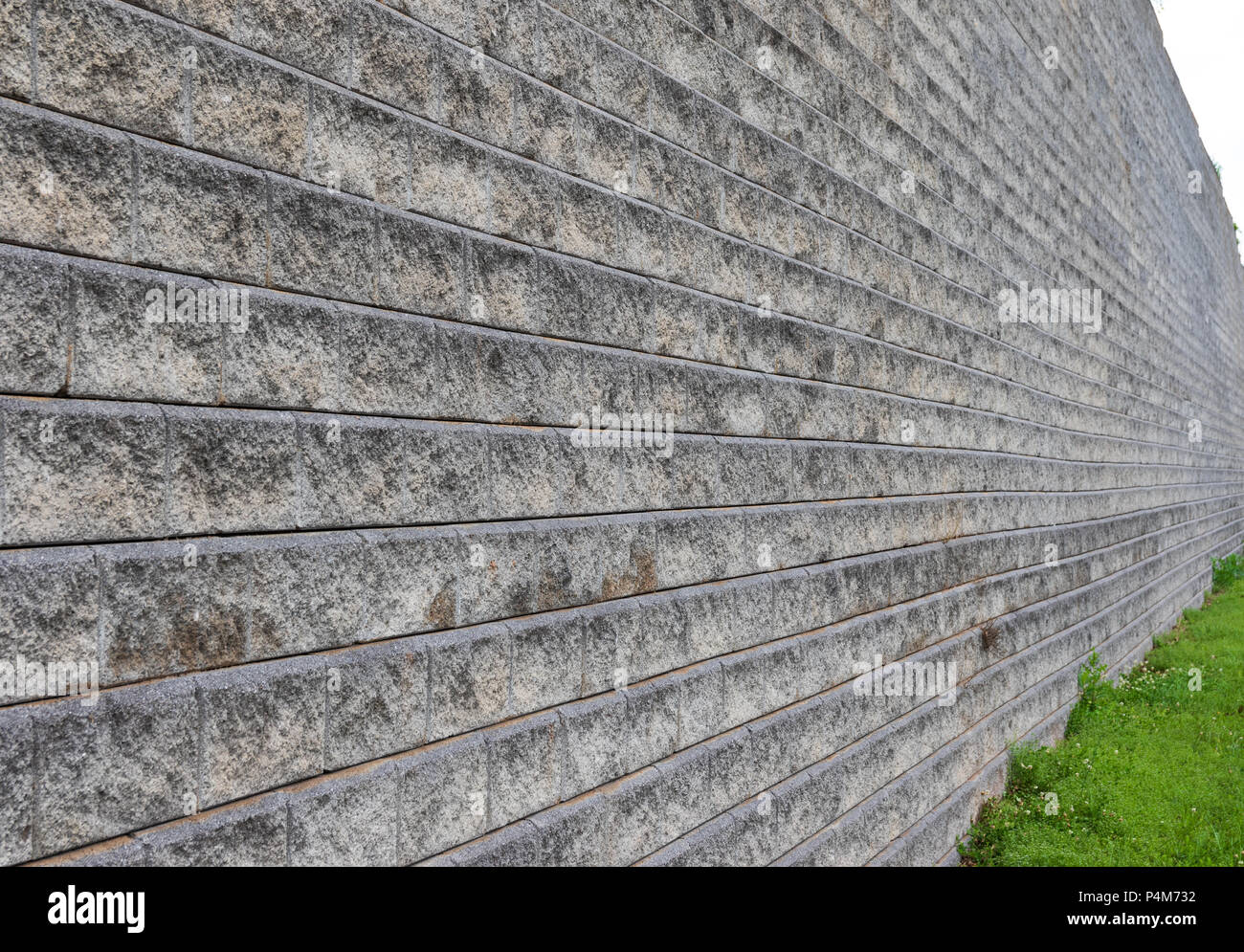 A concrete wall, built of blocks creating horizontal rows, with a ...