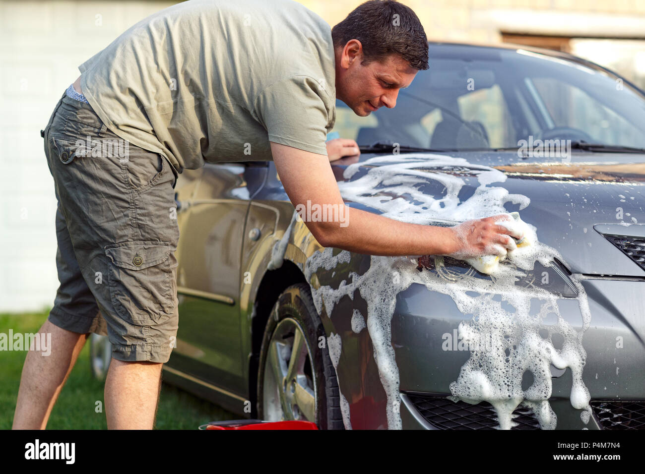 Handsome man washing car with a sponge and foam in the house yard Stock ...
