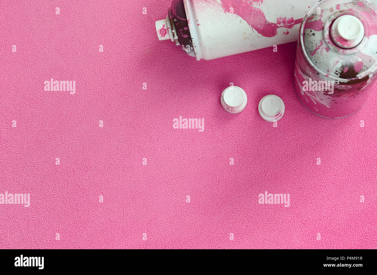 Some used pink aerosol spray cans and nozzles with paint drips lies on ...