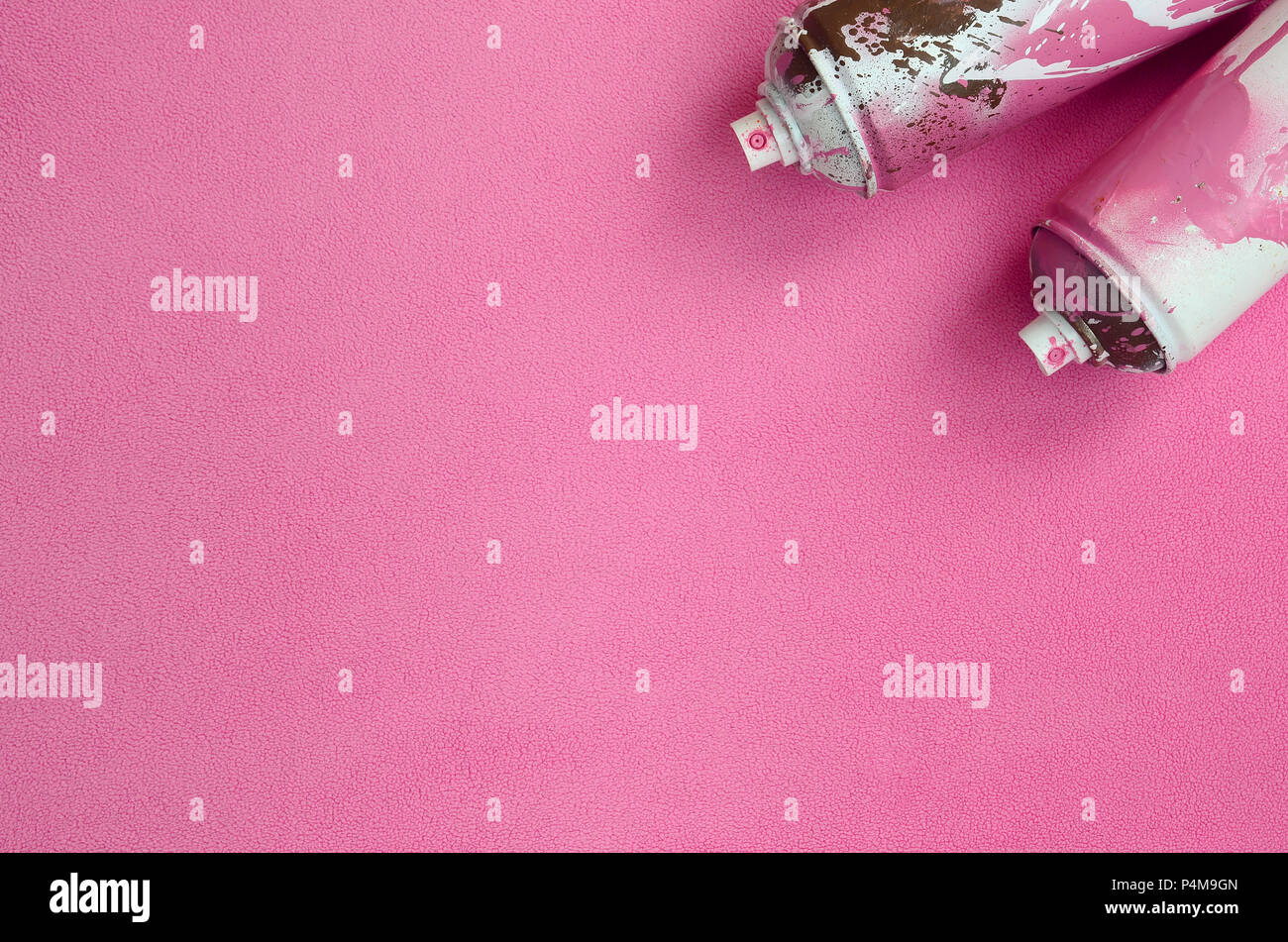 Some used pink aerosol spray cans with paint drips lies on a blanket of ...