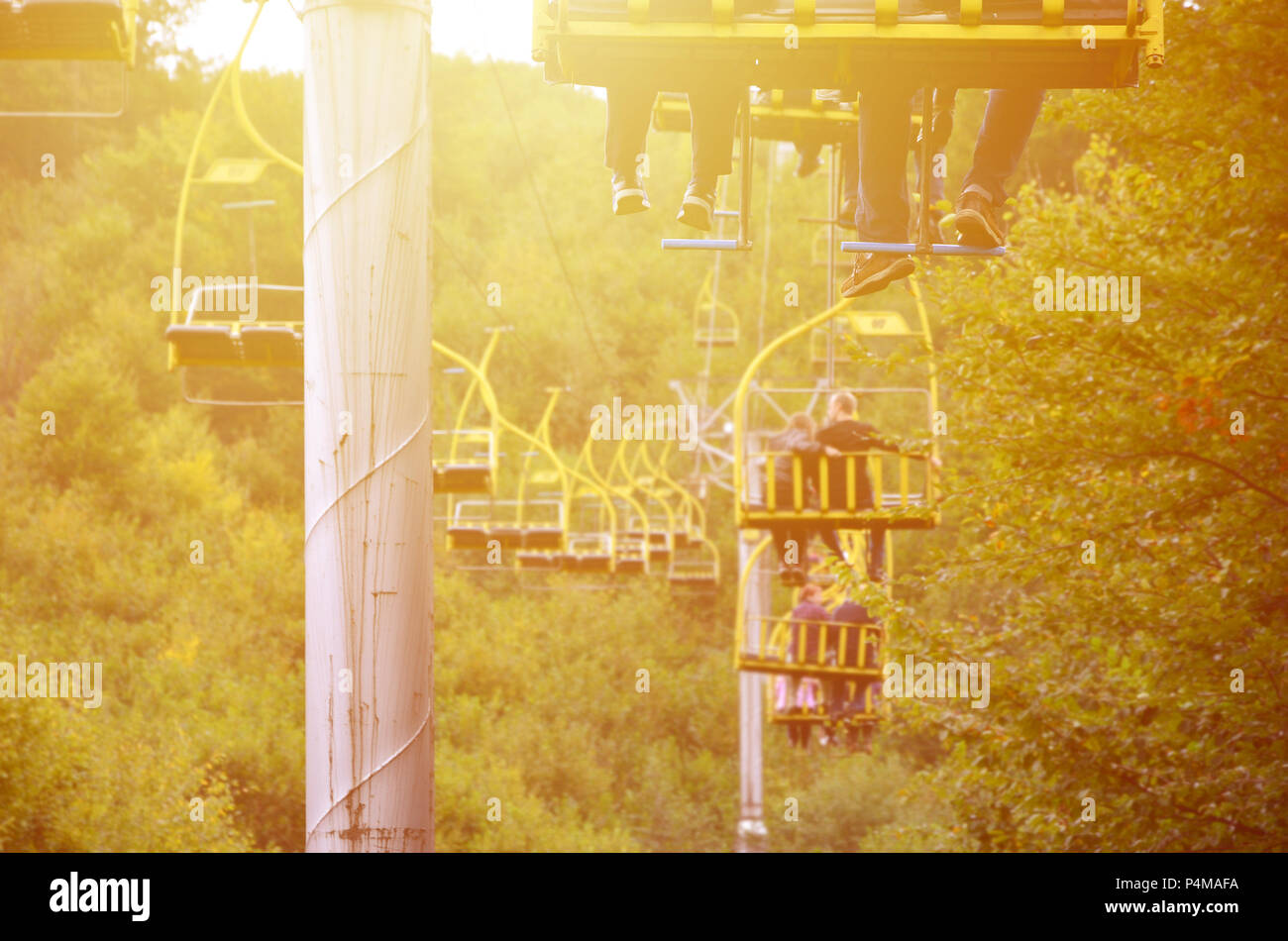 People ride on a cable car. The legs of passengers hang over the ...