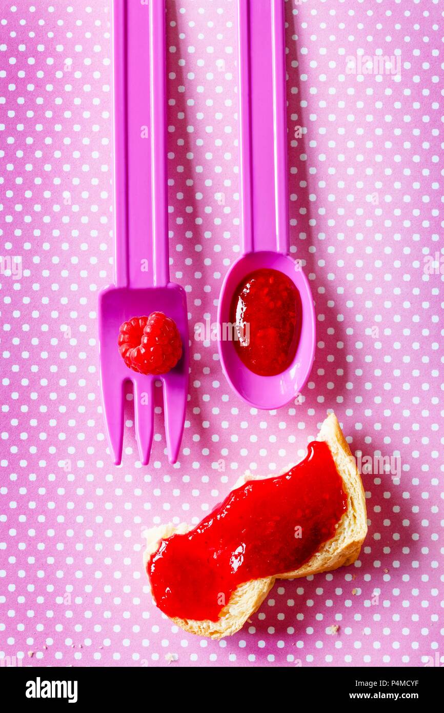 A raspberry face made with cutlery, berries, jam and a piece of bread ...