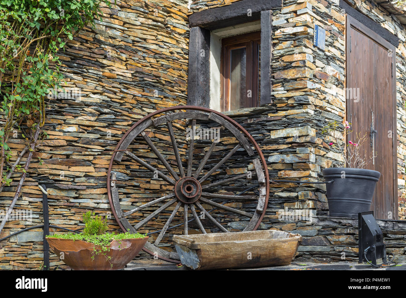 slate stone wall with wagon wheel leaning Stock Photo - Alamy