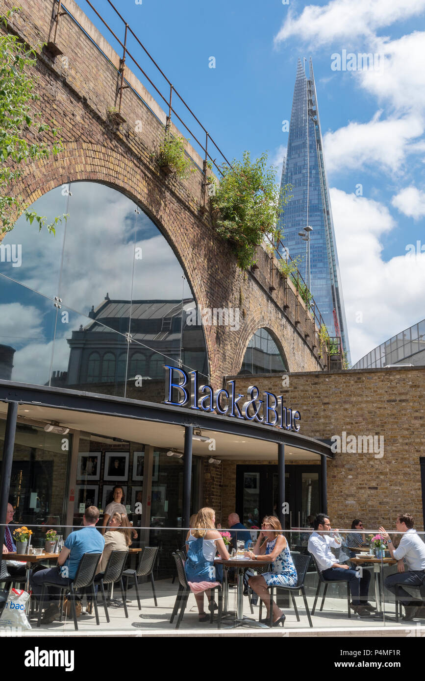 Young people eating at a restaurant at borough market with the shard ...