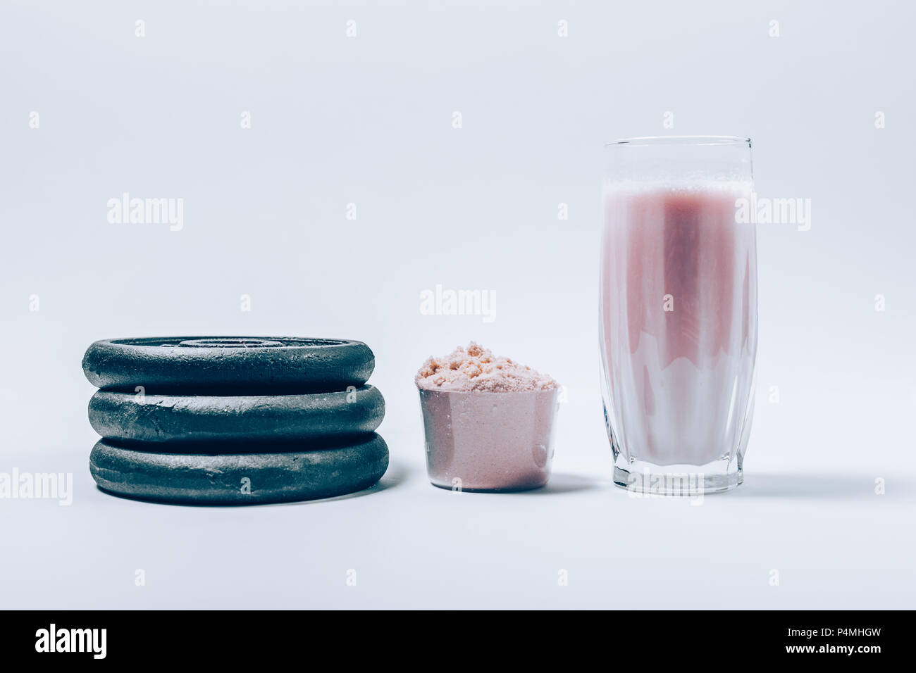 Whey protein cocktail in a glass next to scoop of powder and stack of ...