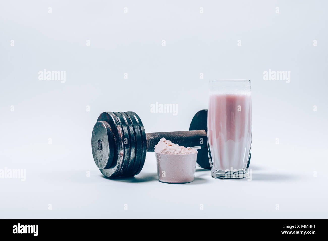 Whey protein shake in a glass next to scoop of powder and dumbbell on a ...