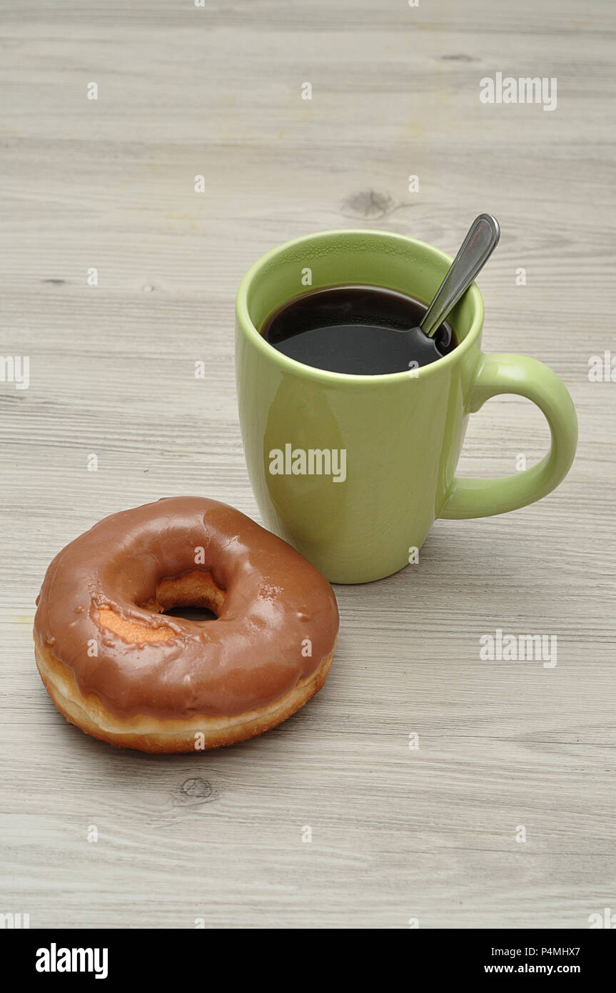 A doughnut with a green mug of coffee Stock Photo - Alamy