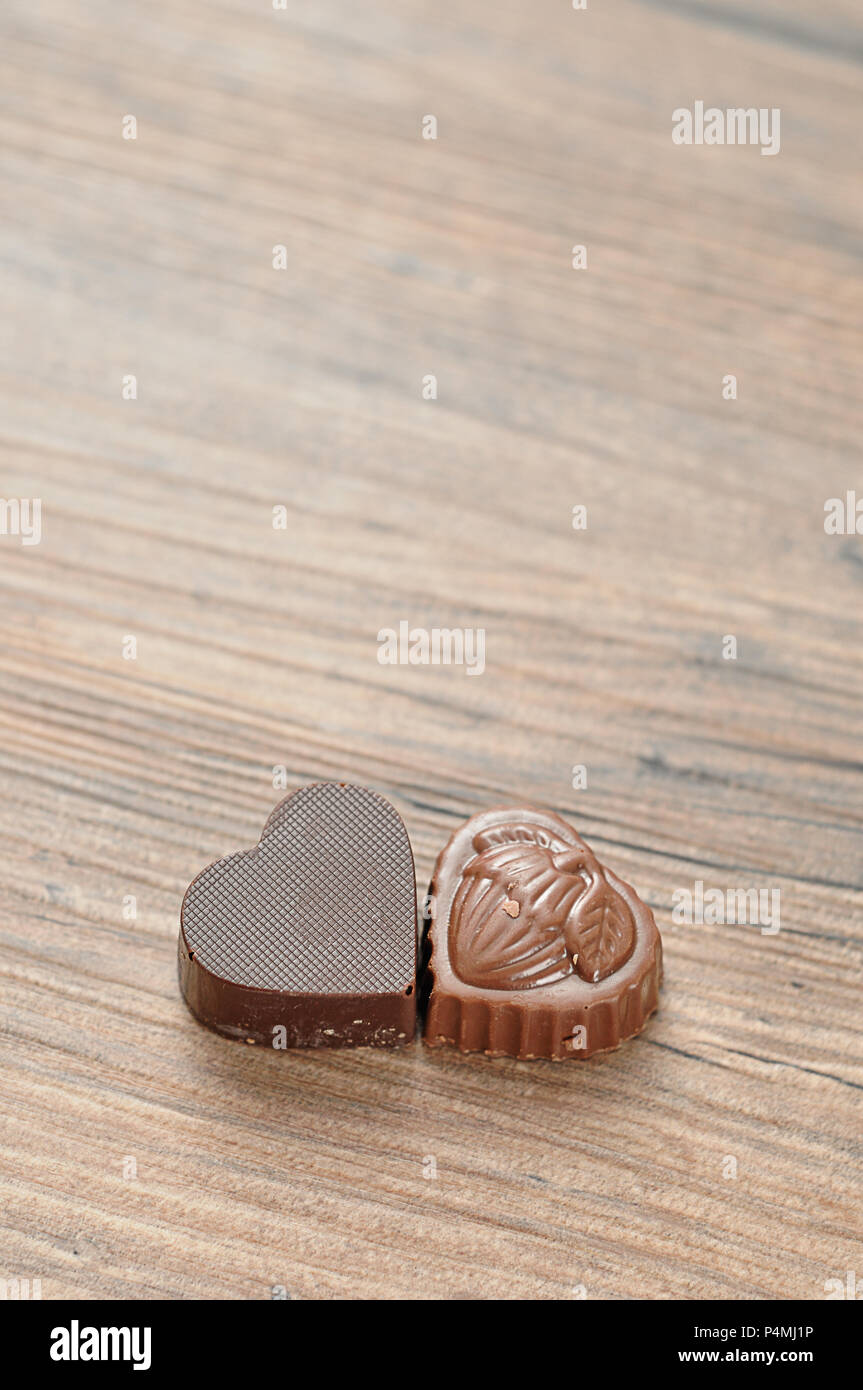 Two heart shape chocolates displayed on a wooden background Stock Photo ...