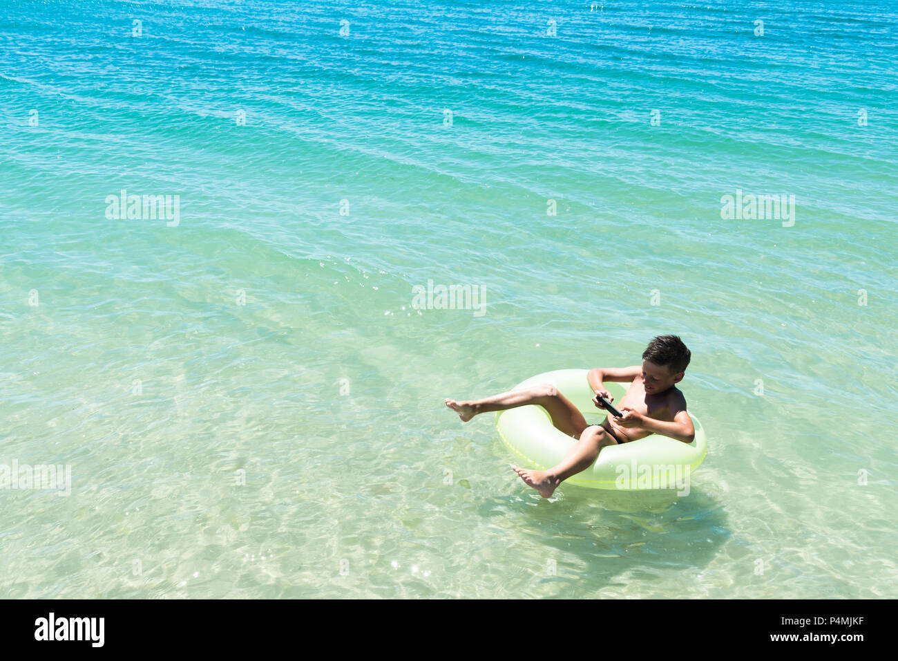 Boy swimming in inflatable ring with smart phone Stock Photo - Alamy