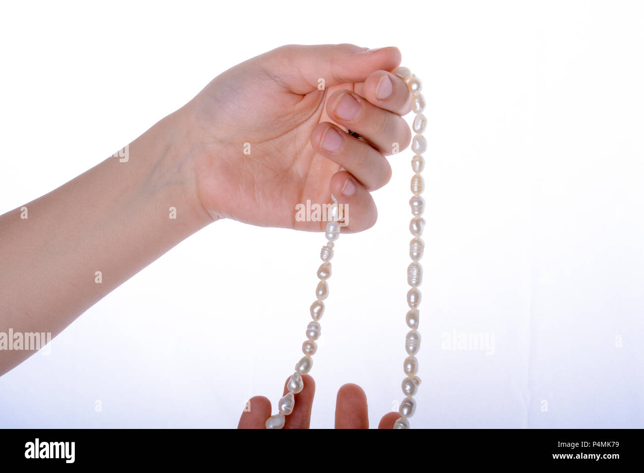 Hand holding a pearl necklace on a white background Stock Photo - Alamy