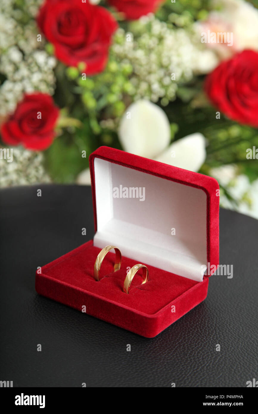Beautiful gold wedding rings in open red box with blur floral ...