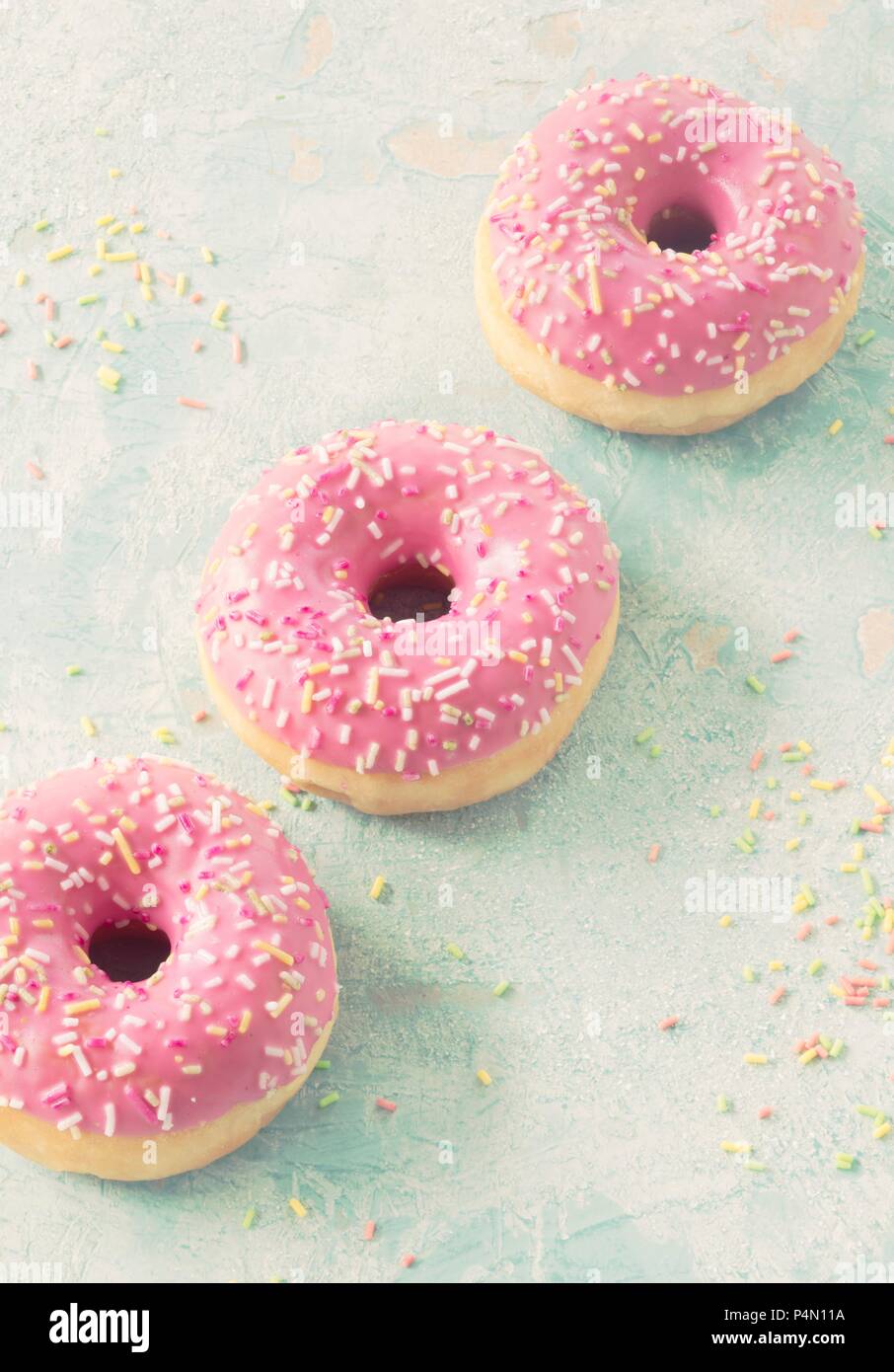 Three pink donuts with sugar sprinkles Stock Photo - Alamy