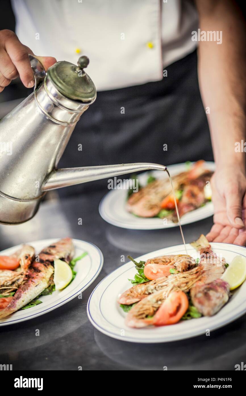Hand finished grilled fish and shrimp on a plate with olive oil Stock ...