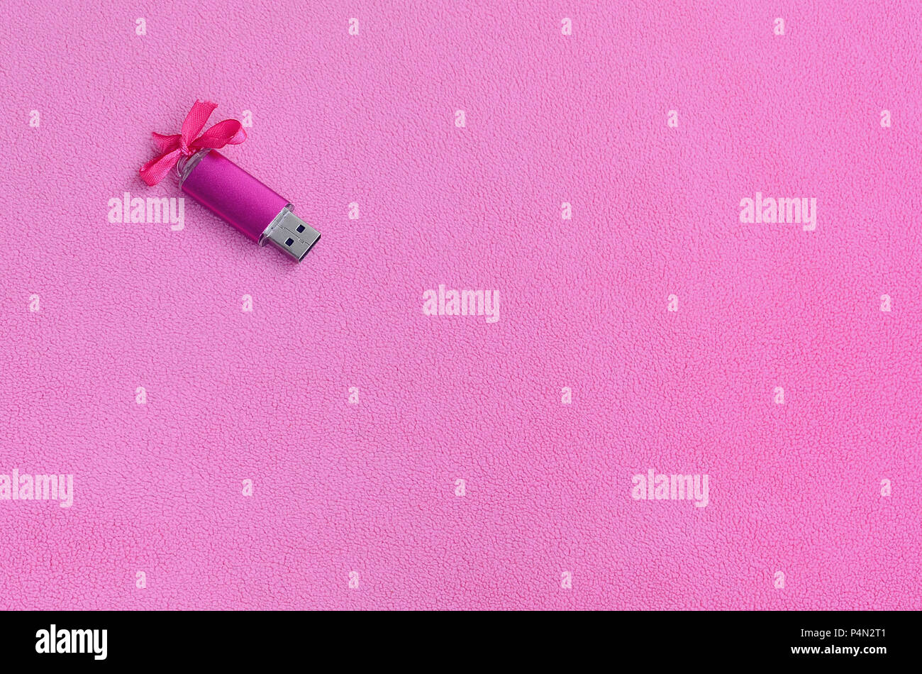 Brilliant pink usb flash memory card with a pink bow lies on a blanket ...