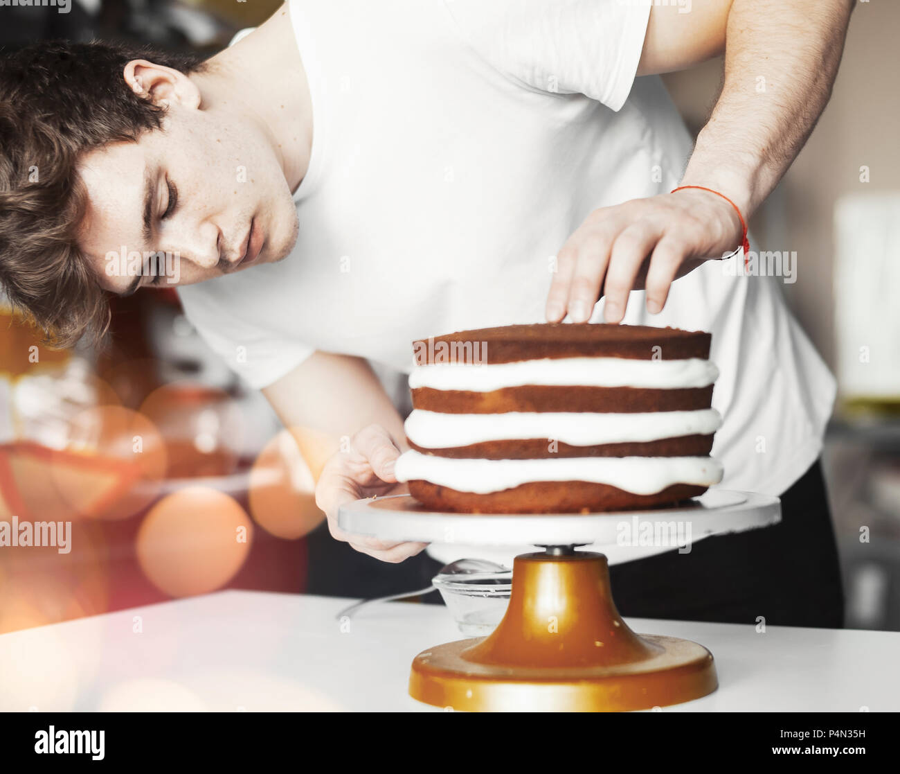 Young attractive man baking chocolate cake with butter cream Stock ...