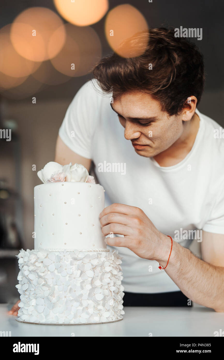 Young attractive man decorating white wedding cake Stock Photo - Alamy