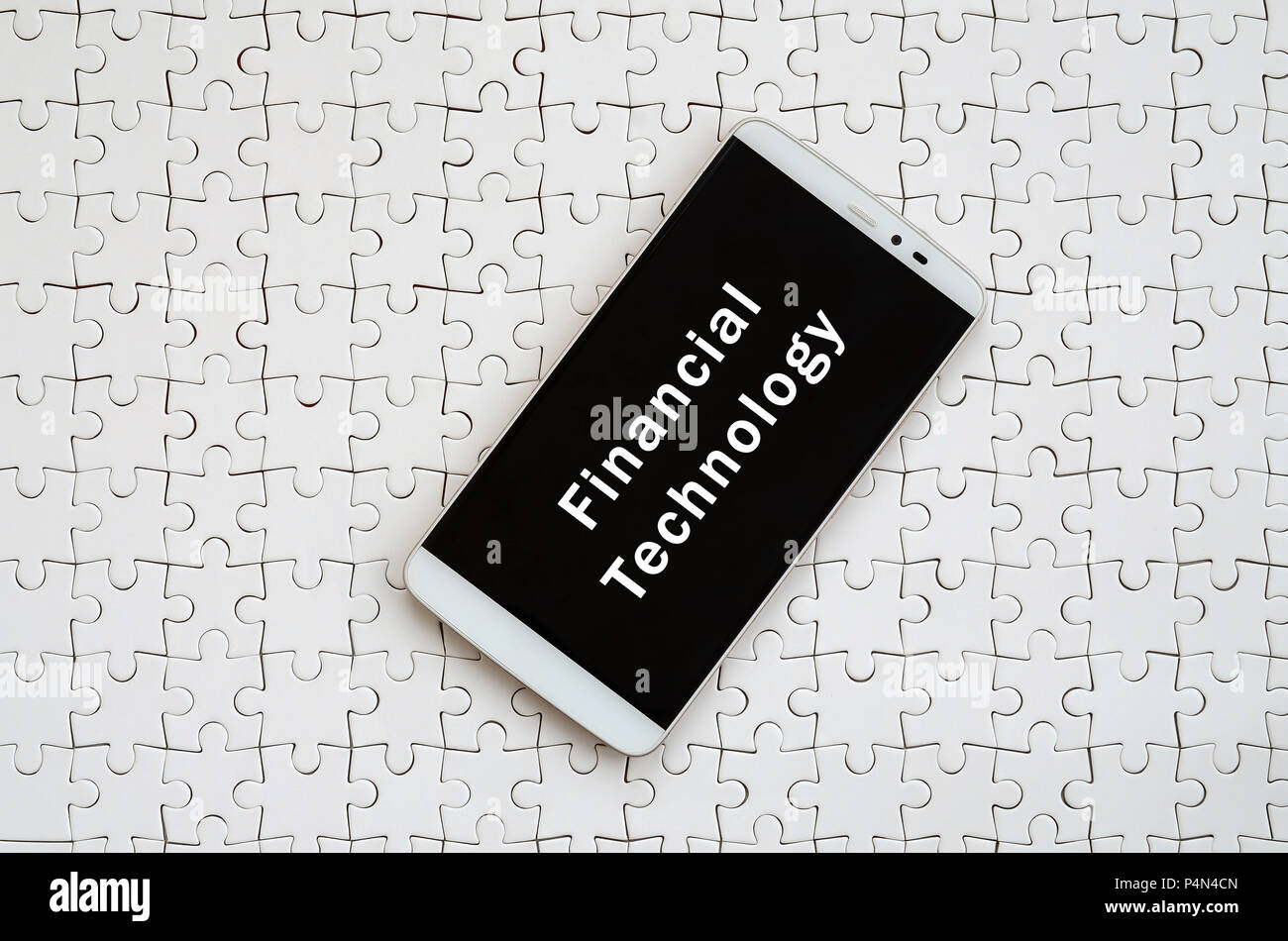 A modern big smartphone with a touch screen lies on a white jigsaw ...