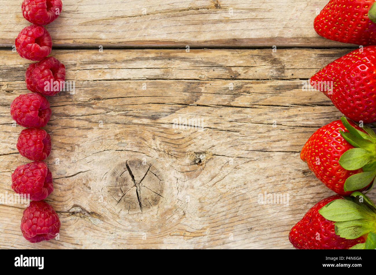 high view of strawberries and raspberries arranged at frame with rustic ...