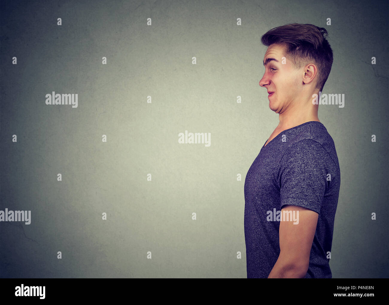 Side view of casual young man looking in aversion and disgust frowning ...