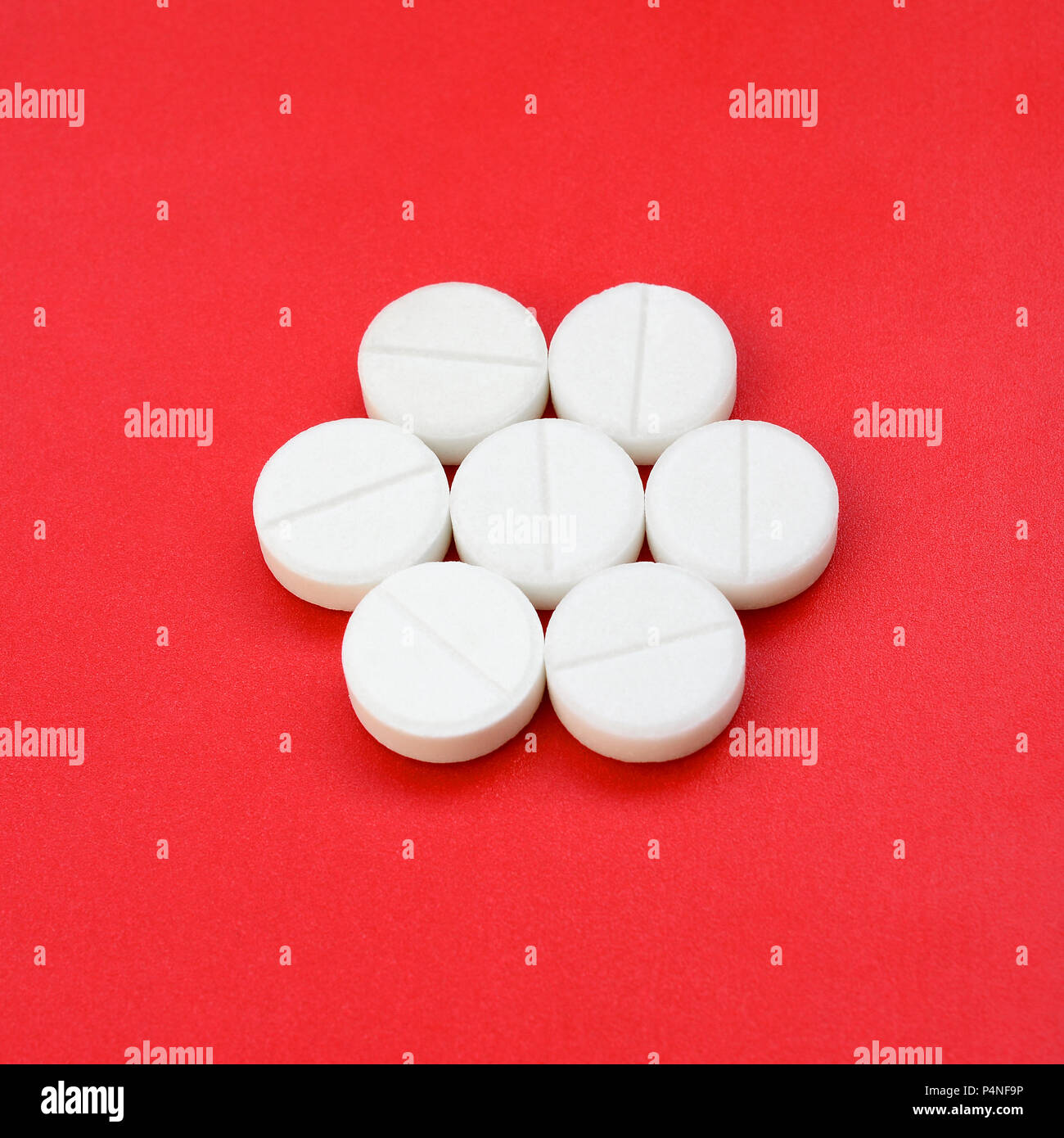 A few white tablets lie on a bright red background surface. Background ...