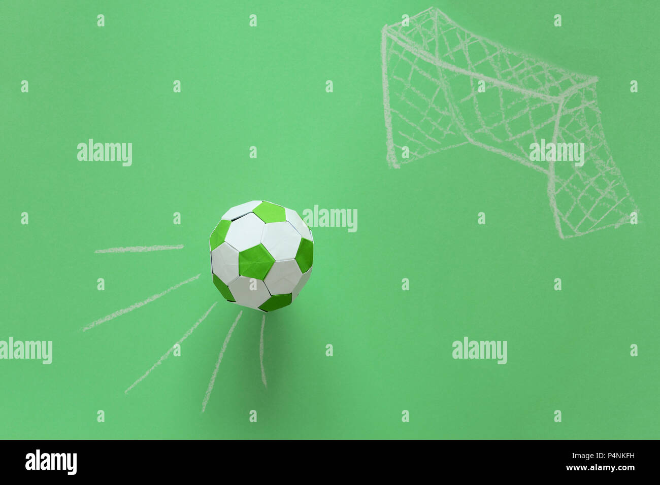 Paper soccer ball flying into goal painted by chalk on green background ...