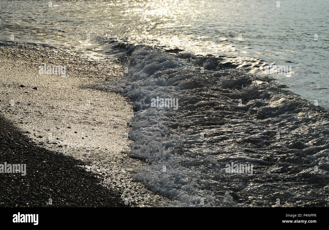 Shiny silver water on the sea pebble beach, early morning sunrise Stock ...