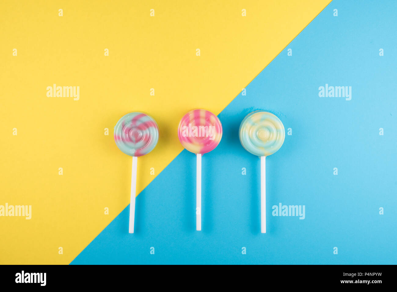 assortment of colorful lollipop over blue and yellow colored background ...