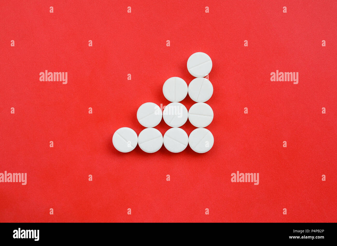 Several white tablets lie on a bright red background in the form of a ...