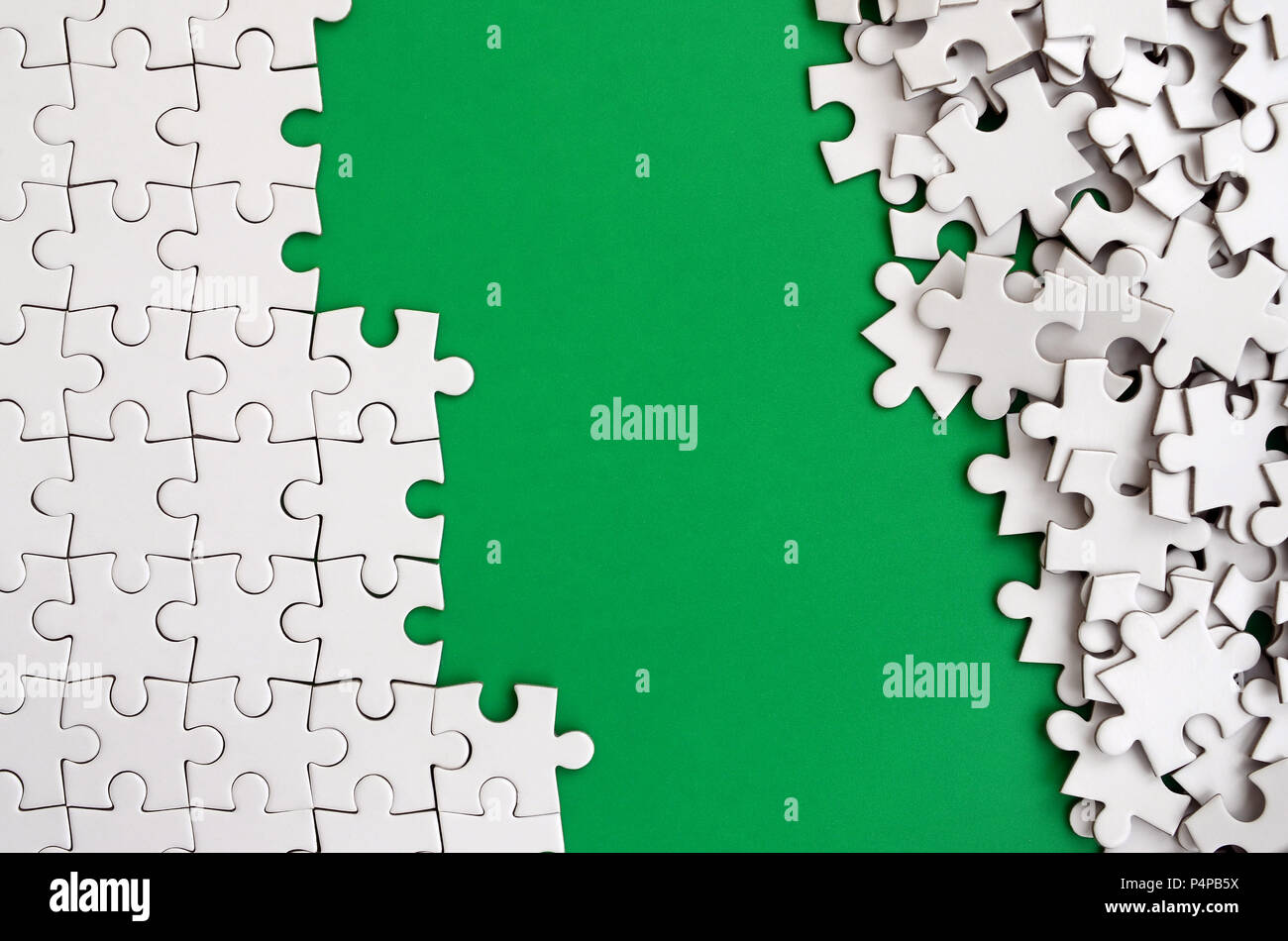 Fragment of a folded white jigsaw puzzle and a pile of uncombed puzzle ...