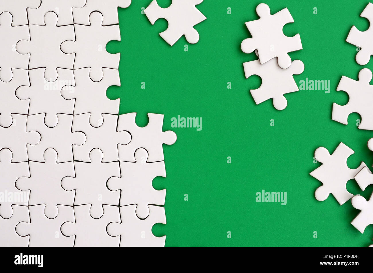 Fragment of a folded white jigsaw puzzle and a pile of uncombed puzzle ...
