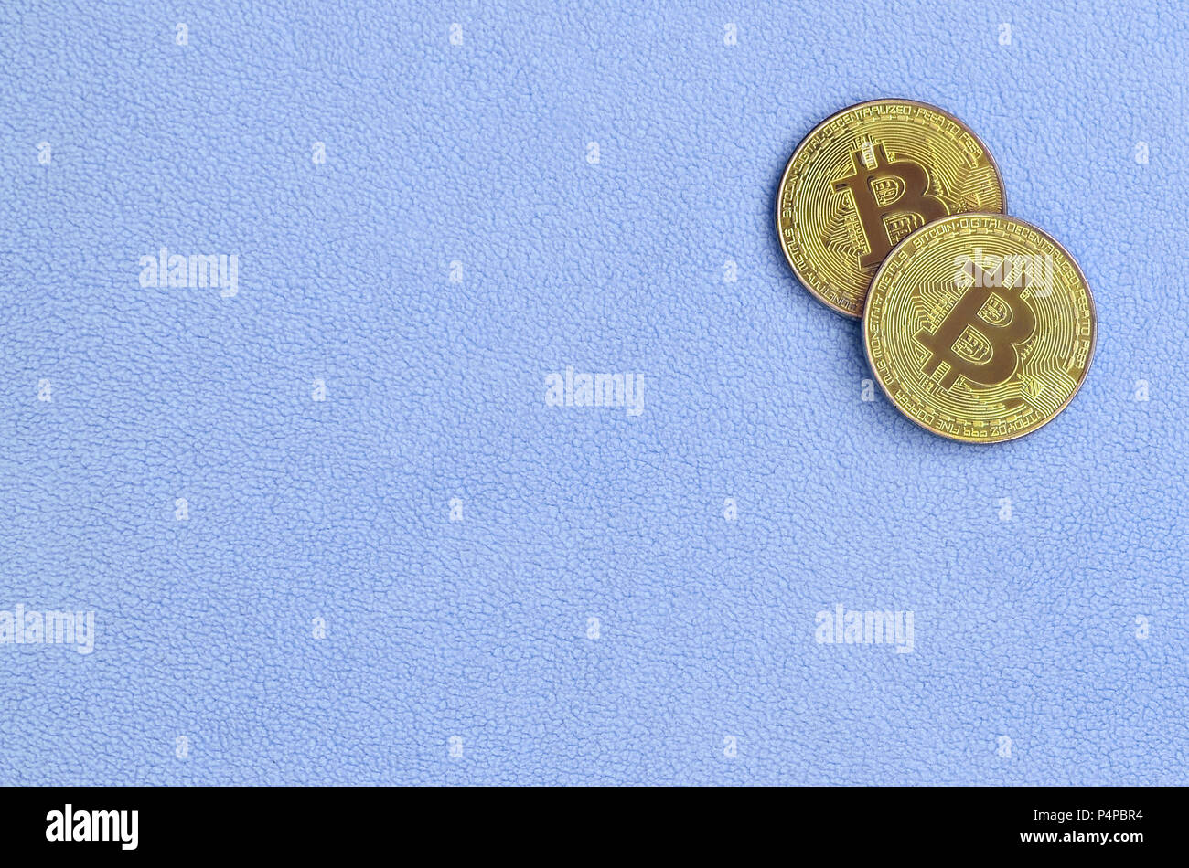 Two golden bitcoins lies on a blanket made of soft and fluffy light ...