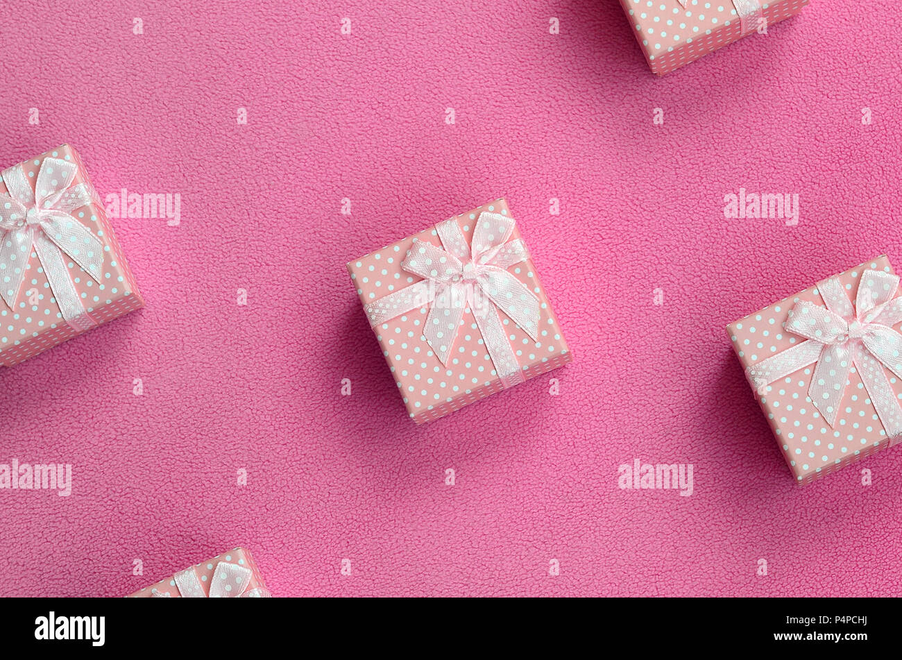 Many small gift boxes in pink color with a small bow lies on a blanket ...