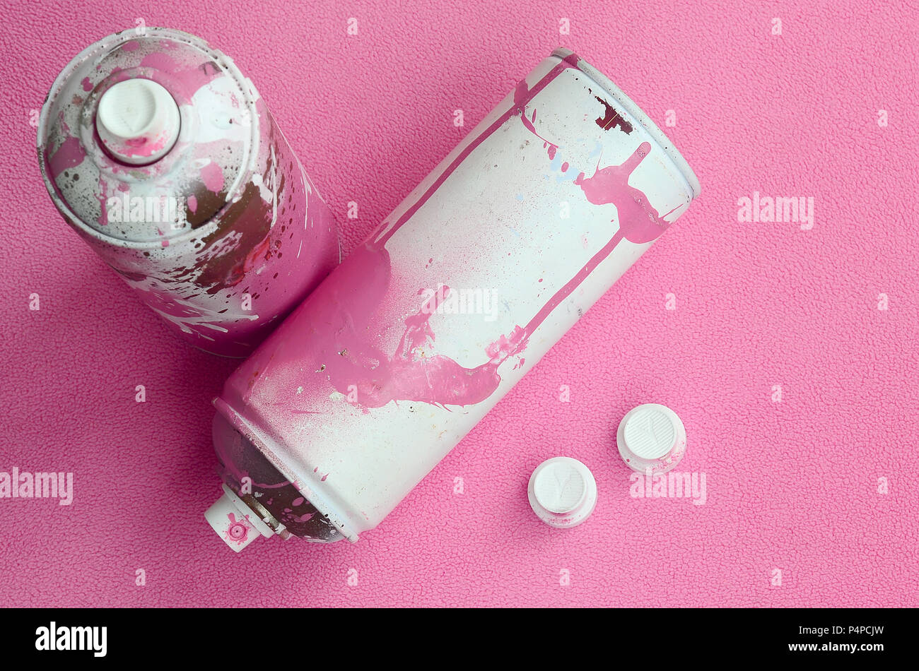 Some used pink aerosol spray cans and nozzles with paint drips lies on ...