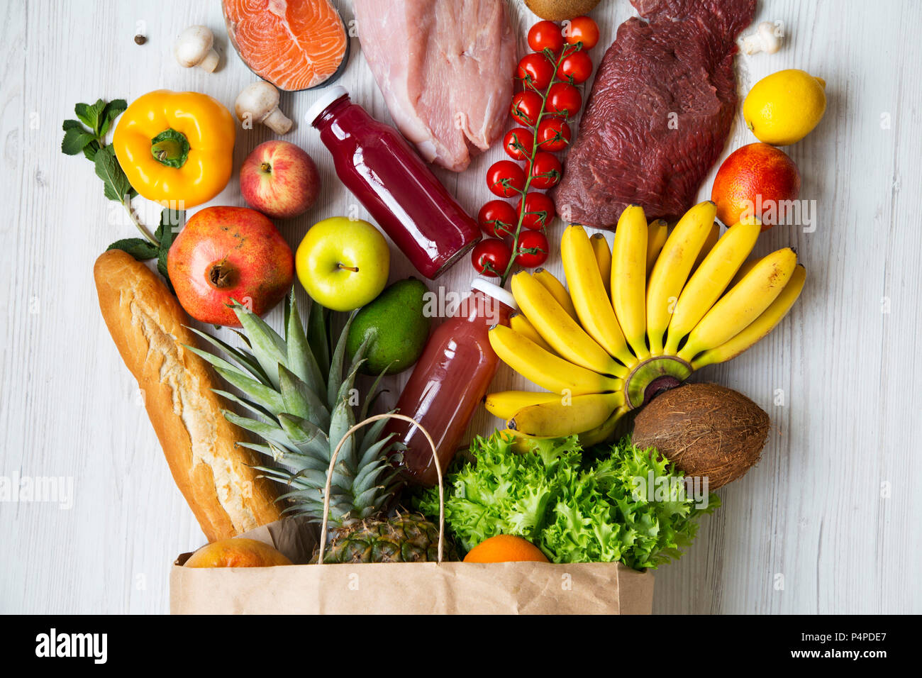 Paper bag of various healthy products on white wooden background ...