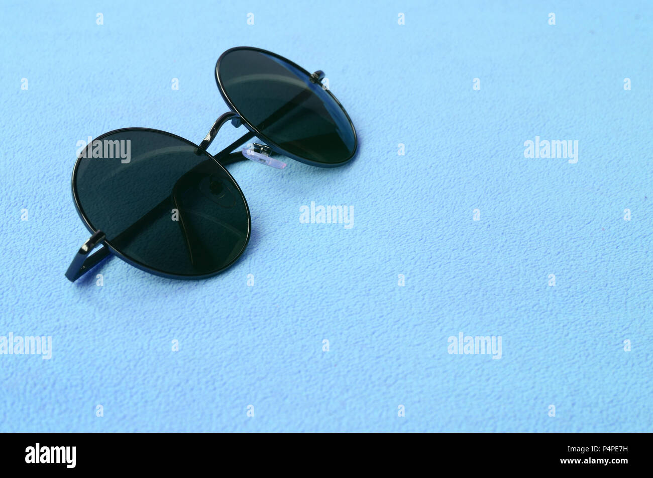 Stylish black sunglasses with round glasses lies on a blanket made of ...