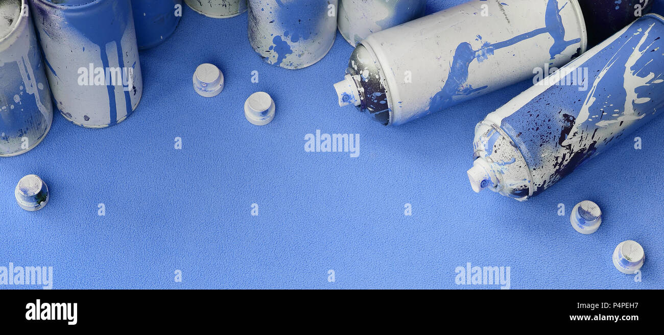 Some used blue aerosol spray cans and nozzles with paint drips lies on ...